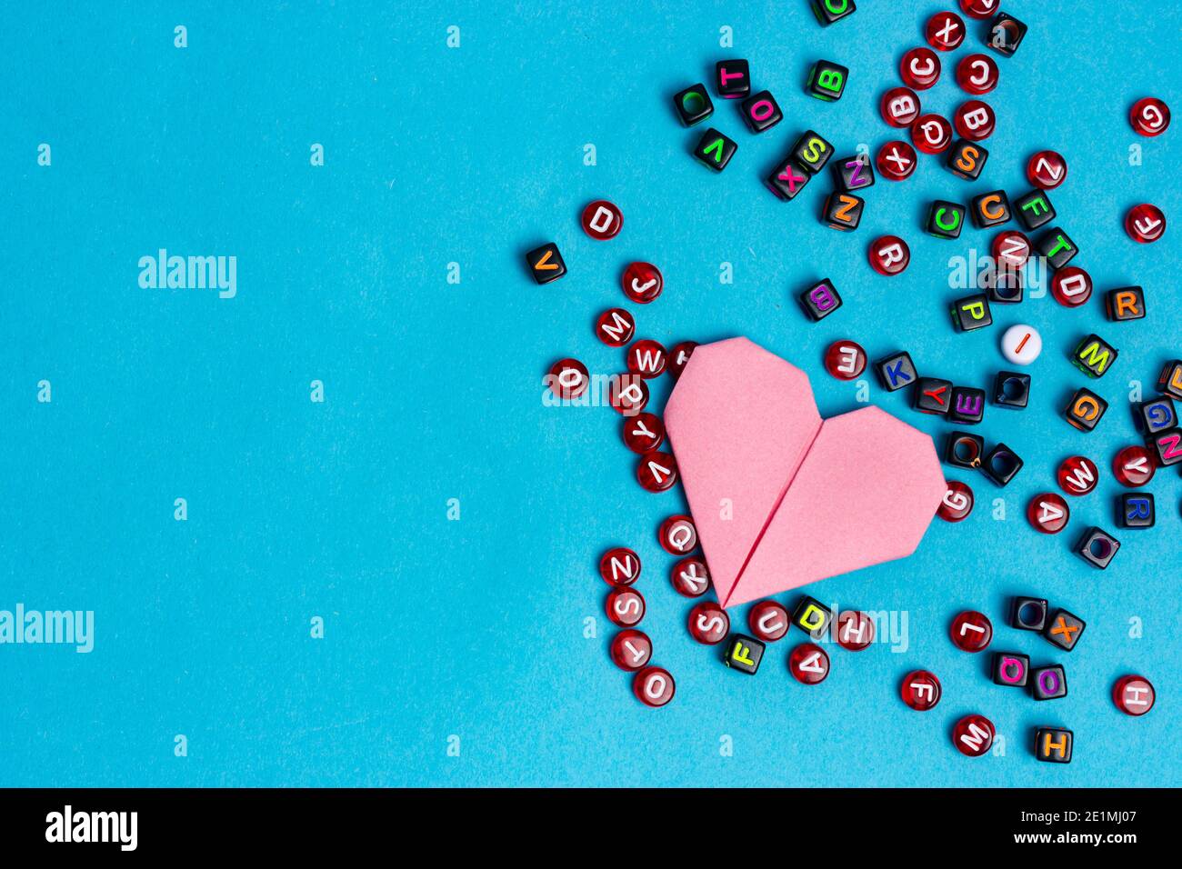 A pink heart among scattered small letters on a blue background Stock ...