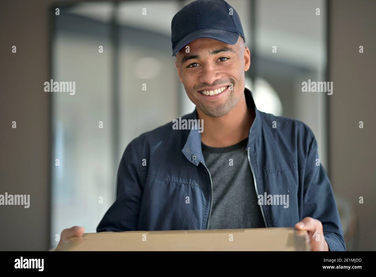 Portrait of afican-american delivery man holding craft box Stock Photo ...