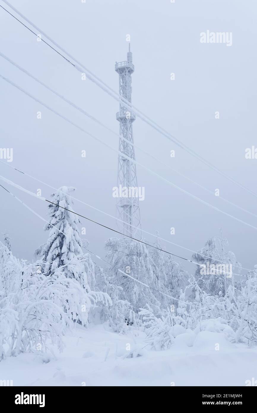 ice-covered cell tower over a snowy forest on top of a mountain against ...