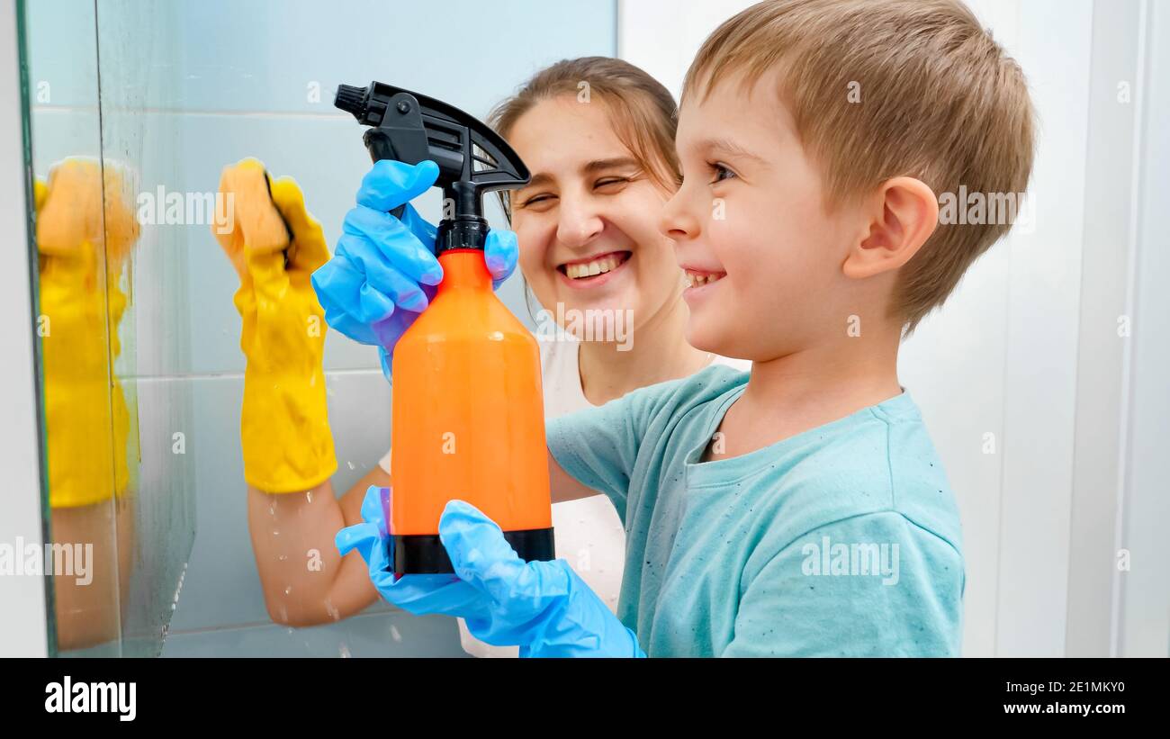 Little toddler boy applying chemical detergent from spray while washing ...