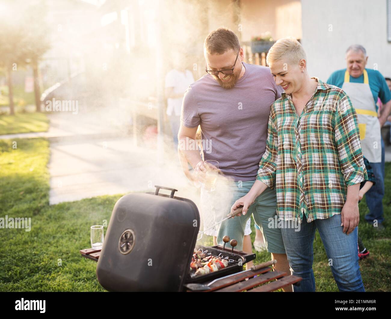 Happy couple making barbeque for their family in their backyard Stock ...