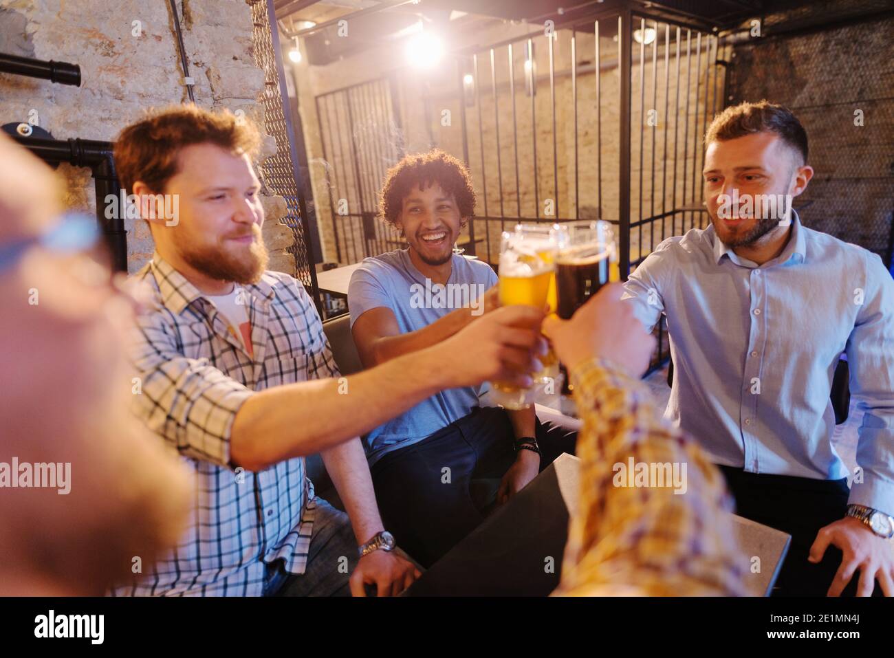 Happy four friends making a toast with beer while sitting in pub Stock ...