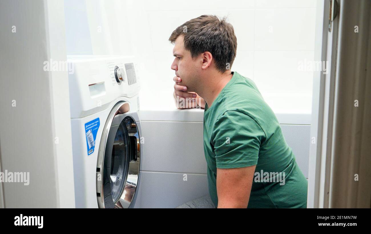 Confused man setting washing laundry machine. Male struggling and ...