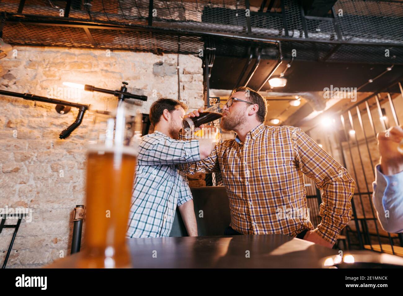 Two men drinking beer with crossed arms . Pub interior Stock Photo - Alamy