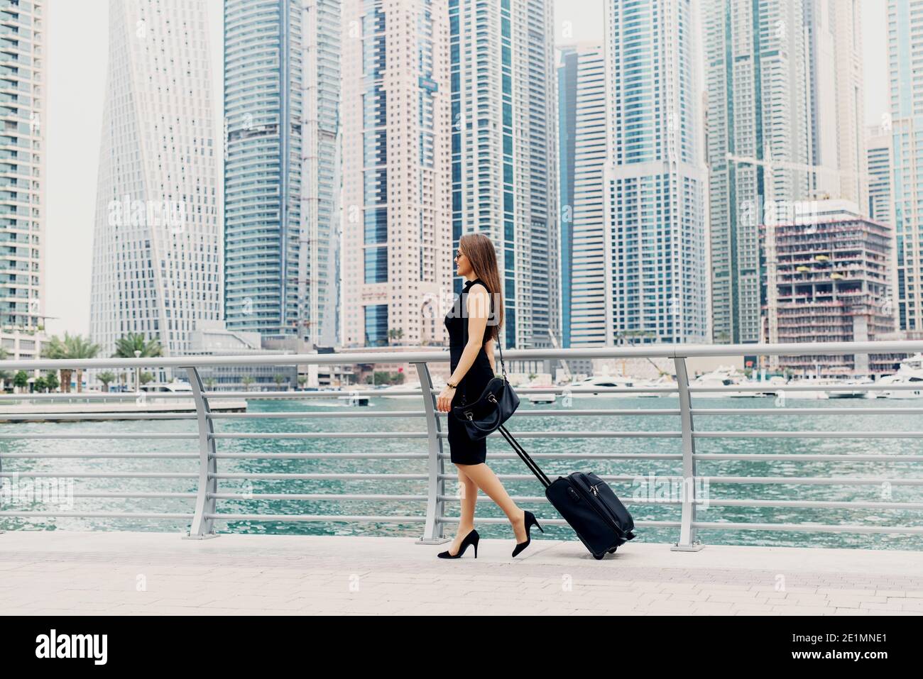 Young modern confident business woman pulling a suitcase in a Dubai ...