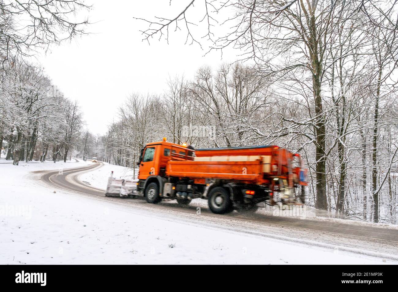 Snow ploughing truck cleans the country road leading through the forest ...