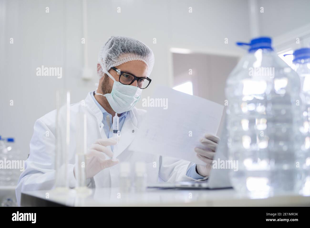 Scientist looking at result of research while sitting at desk. On desk ...