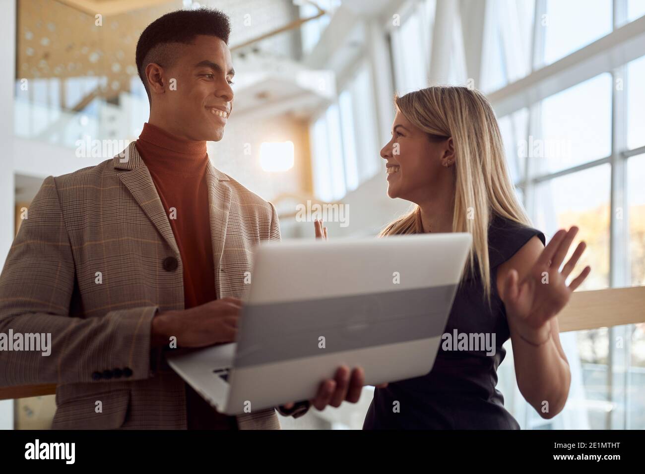 Two colleagues talking about job tasks at company's hallway in a ...
