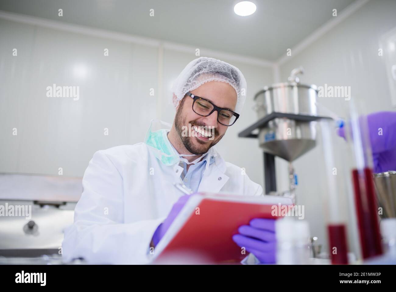 Smilling man writing test results while sitting in the lab Stock Photo ...