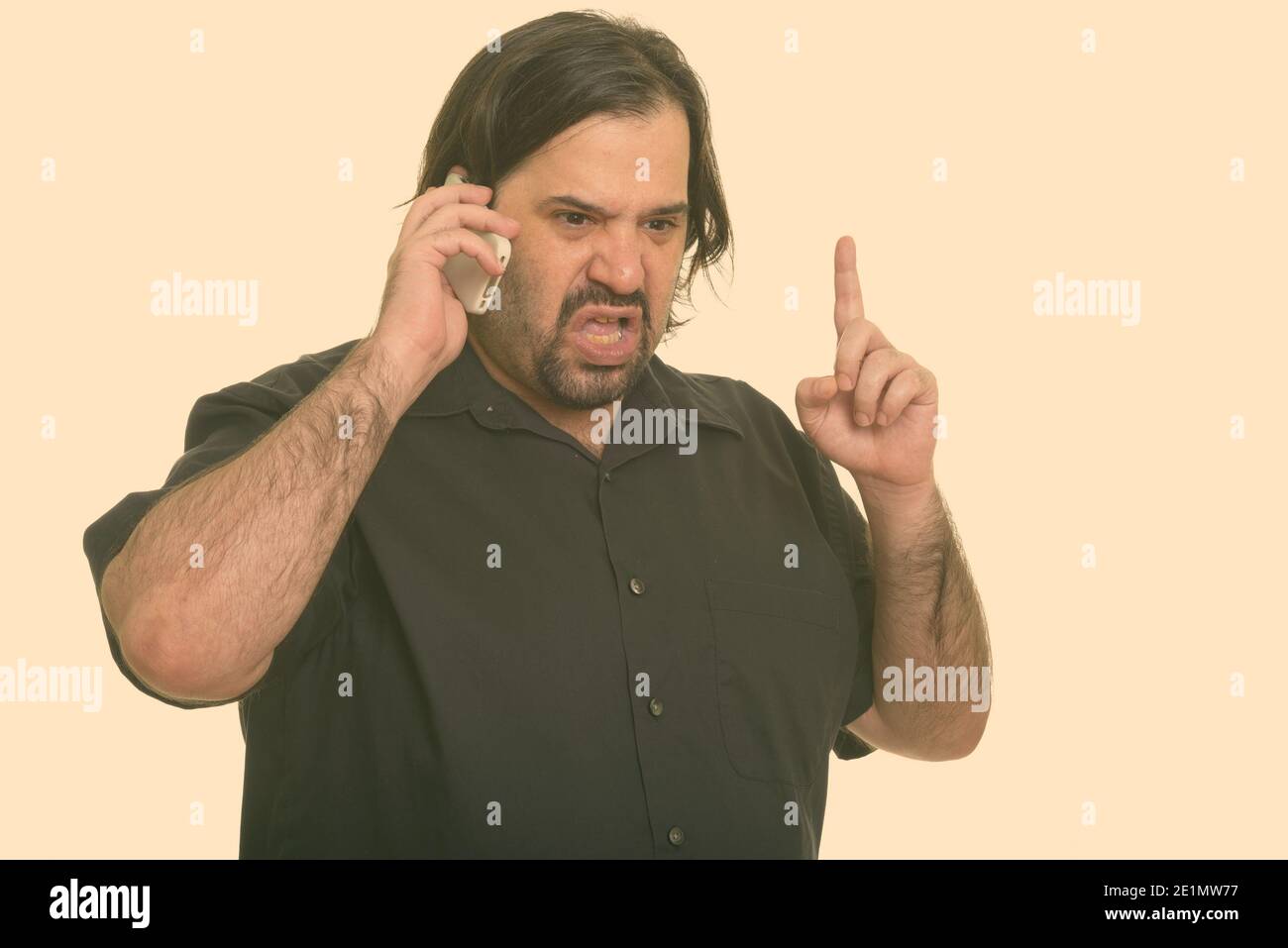 Angry fat Caucasian man talking on mobile phone while pointing finger ...