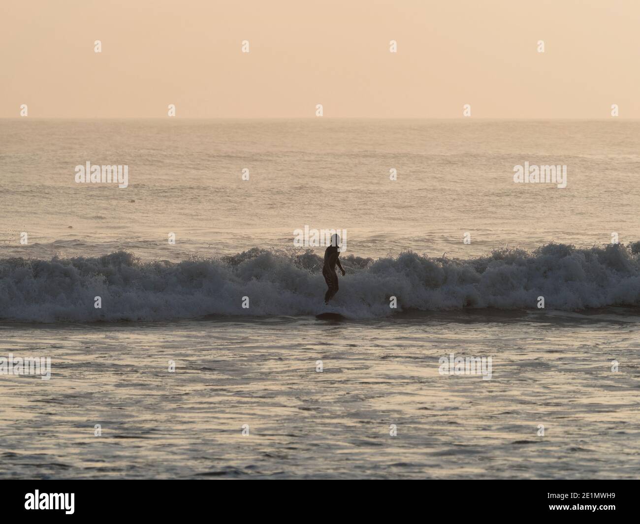 Panoramic sunset view of surfer riding a wave at Huanchaco beach ...