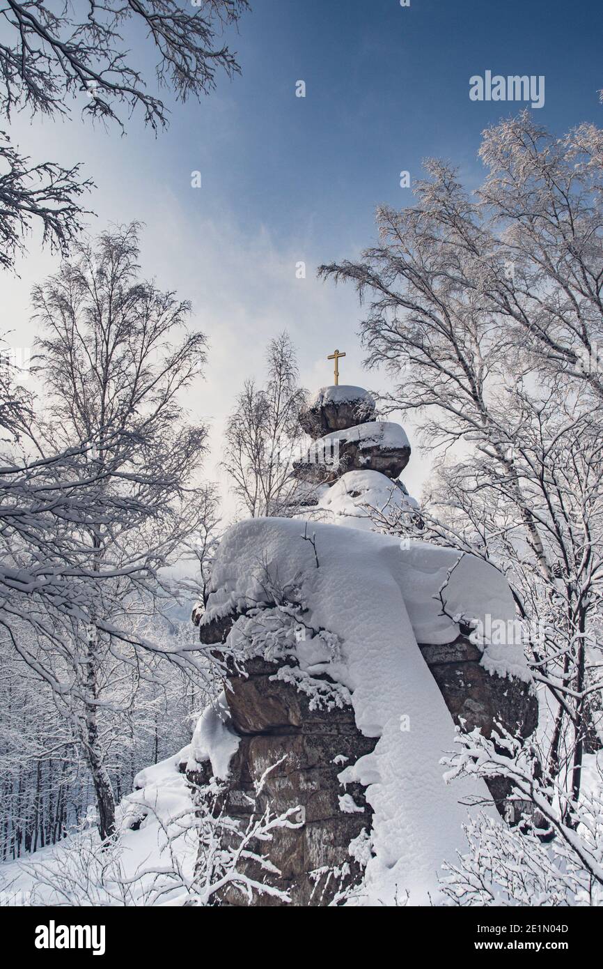 Christian cross on rock in winter forest. Golden cross on stone with ...