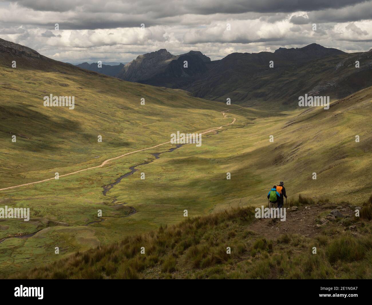 Panorama view of two hikers on Cordillera Huayhuash Circuit trail path ...