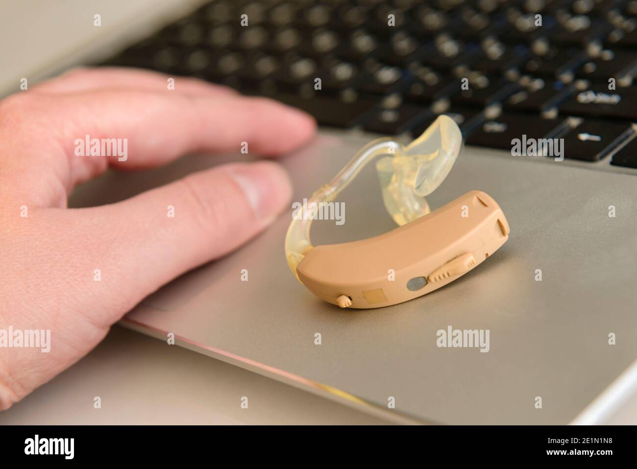 Hearing aid lying on a laptop, hand visible in the background Stock ...