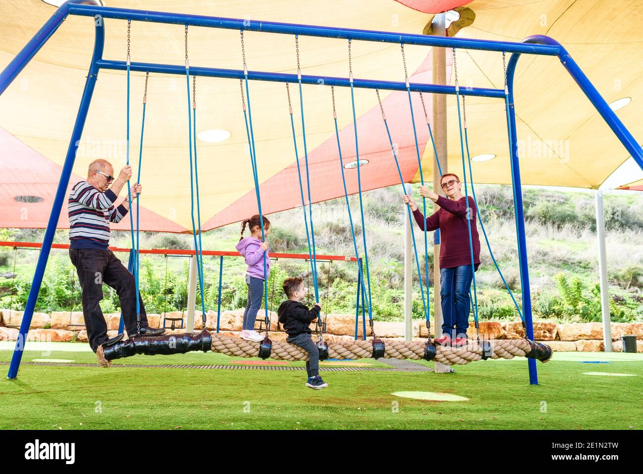 Happy family on balance rope in playground Stock Photo - Alamy