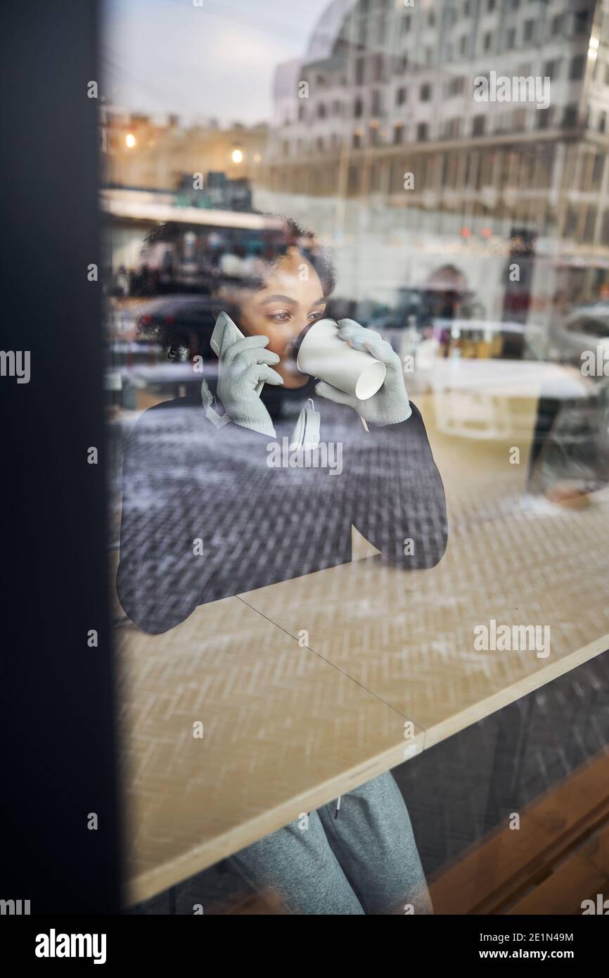 Female cafe customer drinking while talking on a cellphone Stock Photo ...