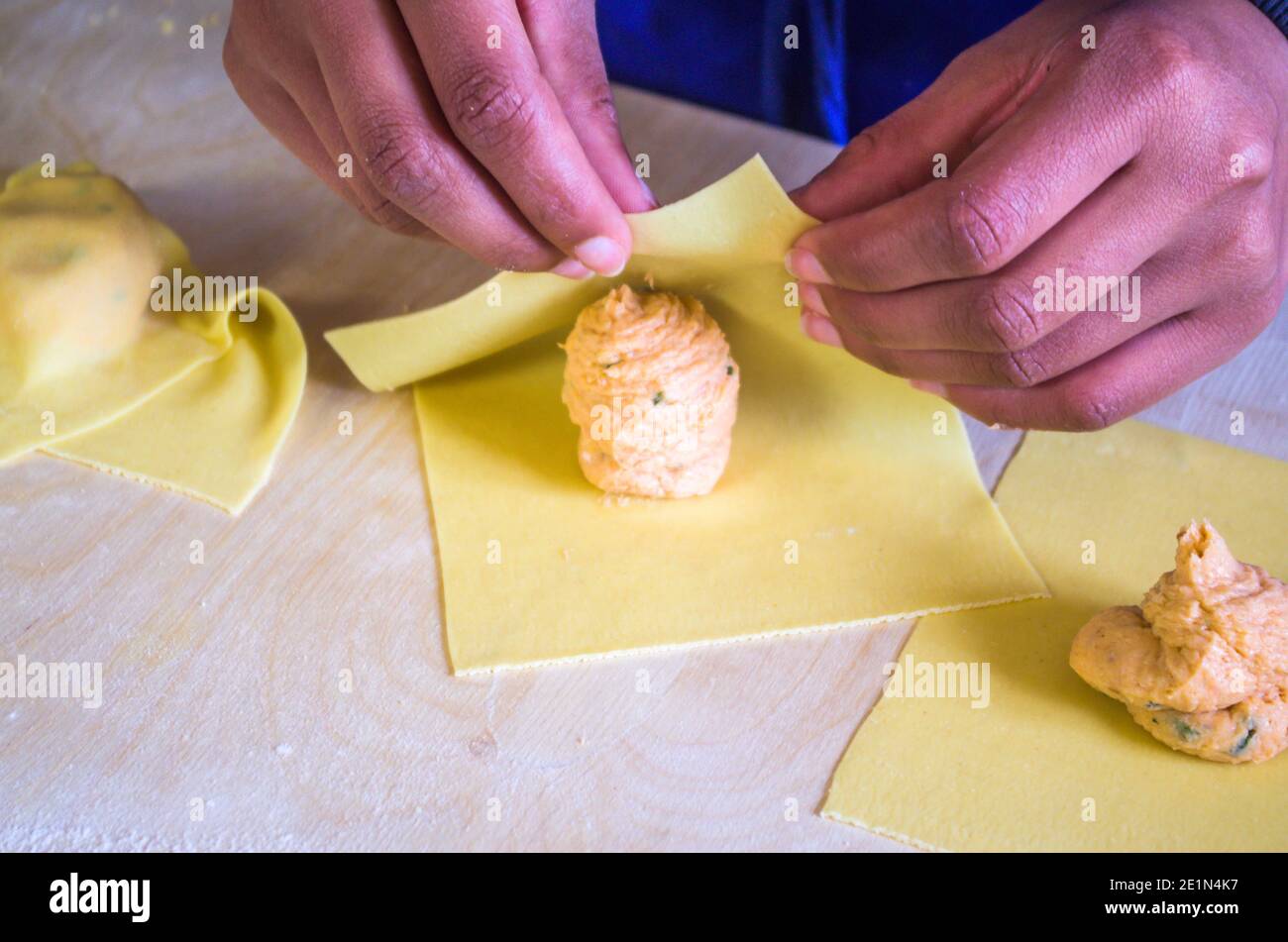 hand of the Italian housewife prepares egg pasta, ravioli and tortelli ...