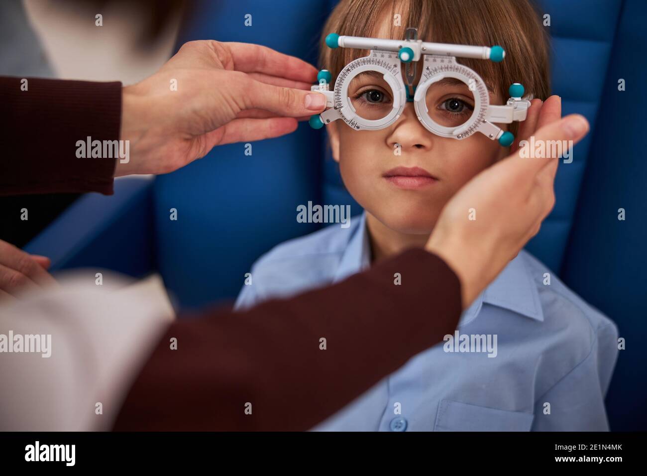 Adult putting a trial frame on kid eyes Stock Photo - Alamy