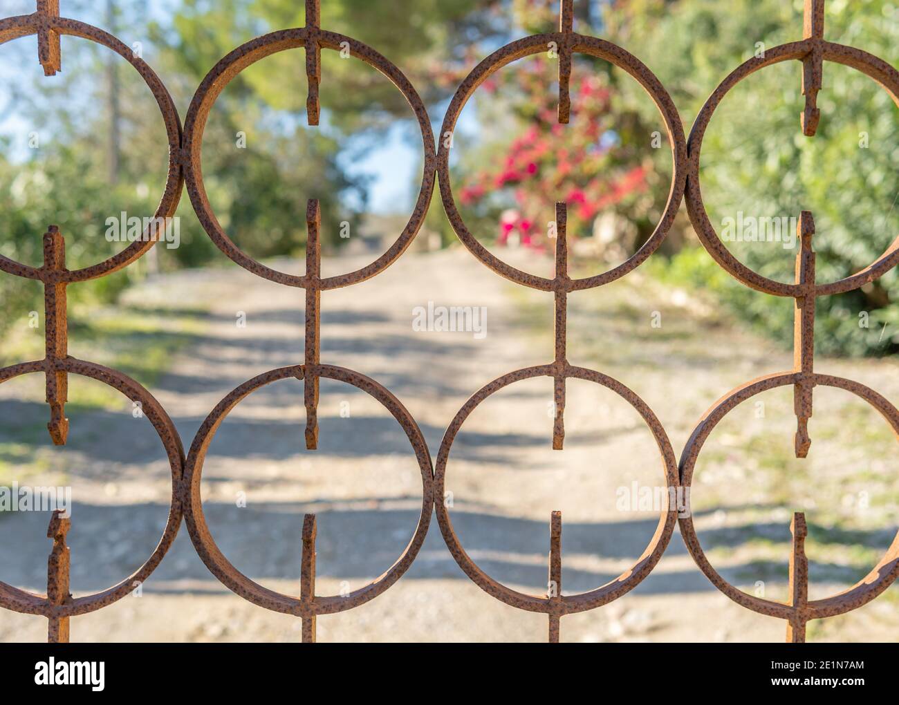 Focused rusty iron fence. In the background, a sunny Mediterranean ...