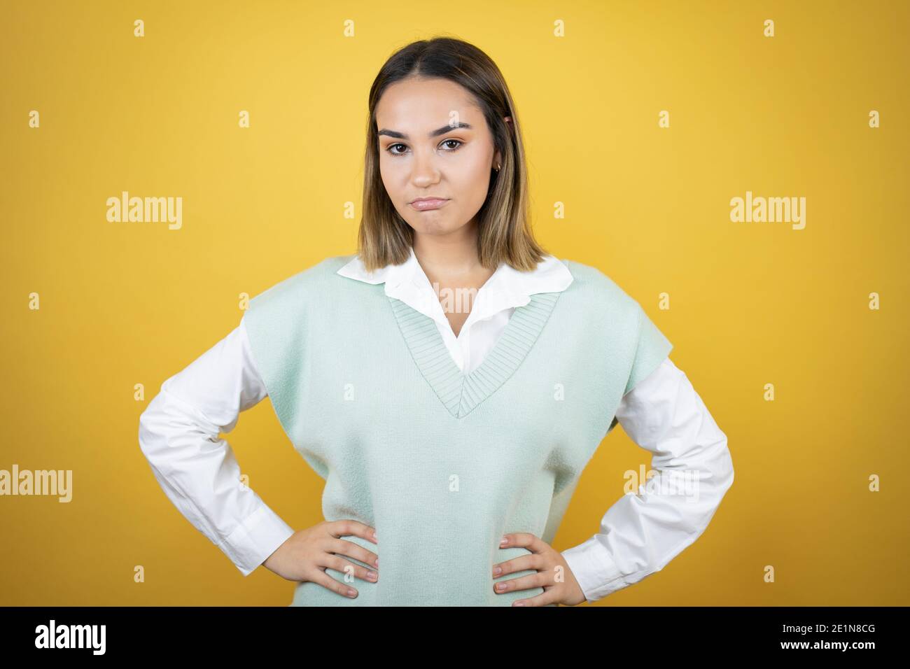 Pretty young woman standing over yellow background skeptic and nervous ...