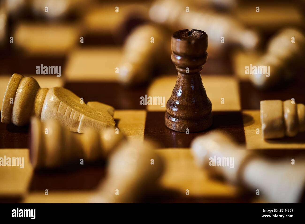 Black rook stands upright on chessboard, surrounded by fallen white ...