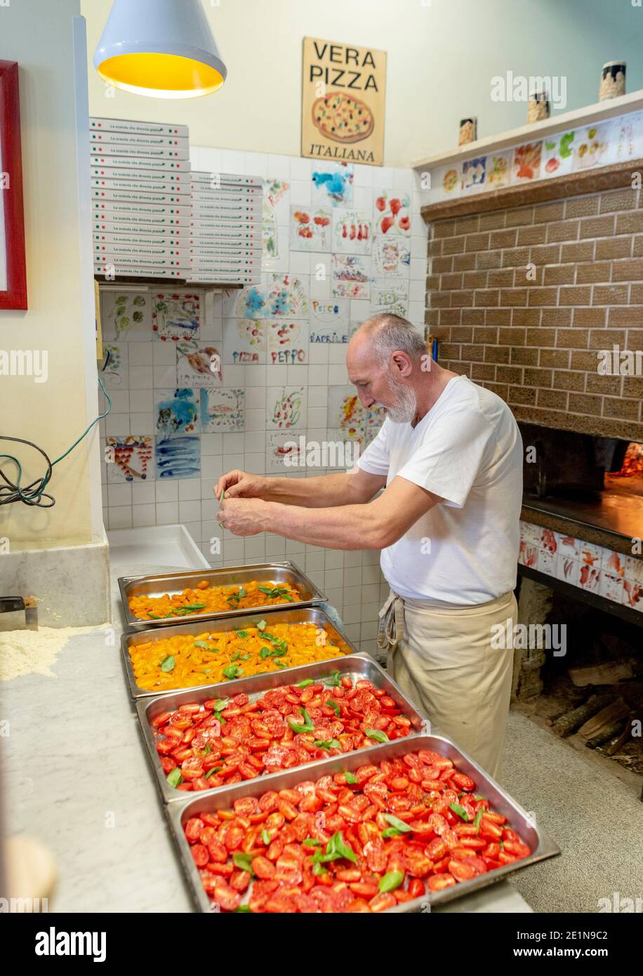 Pizzaiolo pizza chef prepares tomatoes for the pizza Stock Photo - Alamy