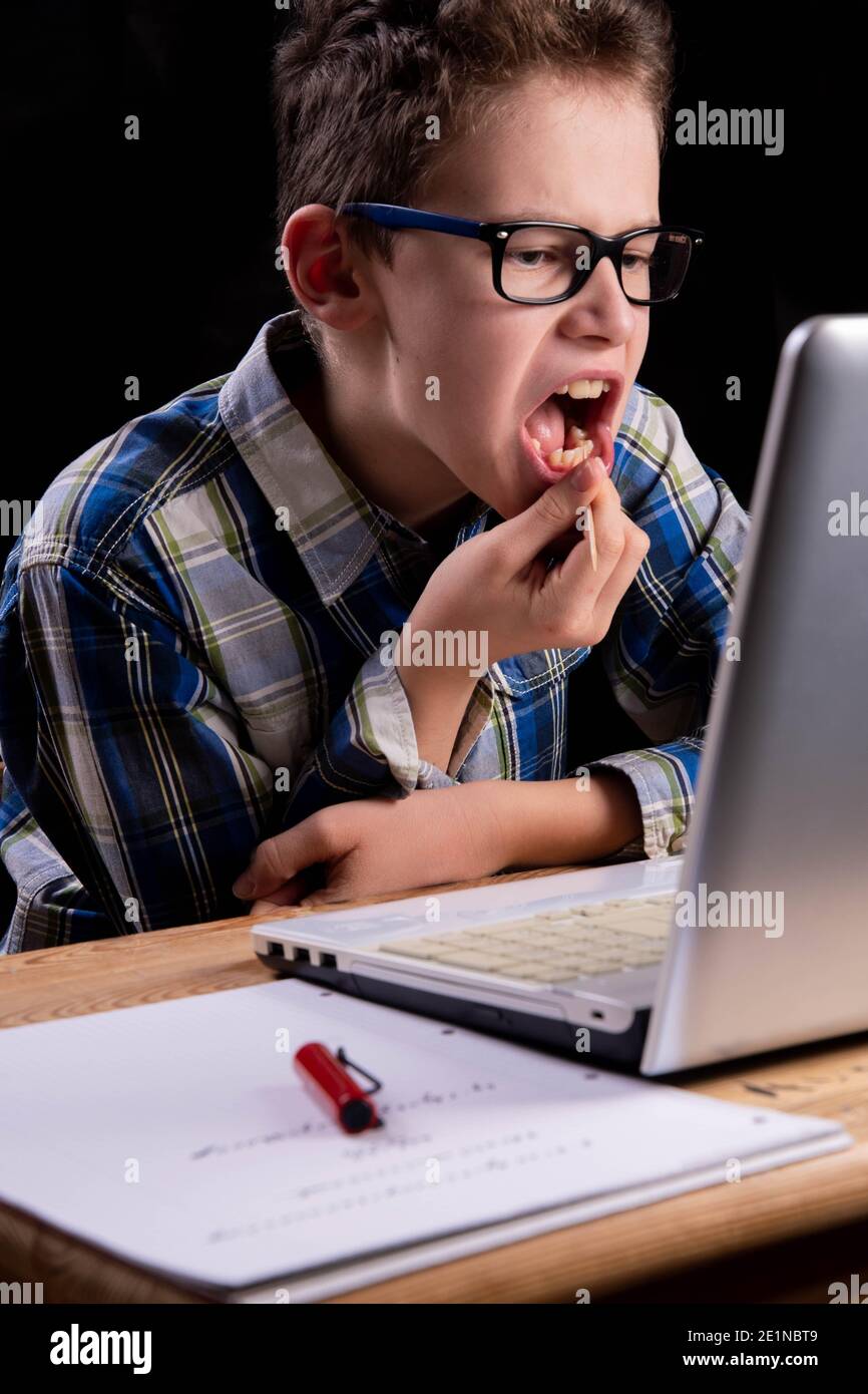 Boy cleans his teeth with toothpick on laptop Stock Photo - Alamy