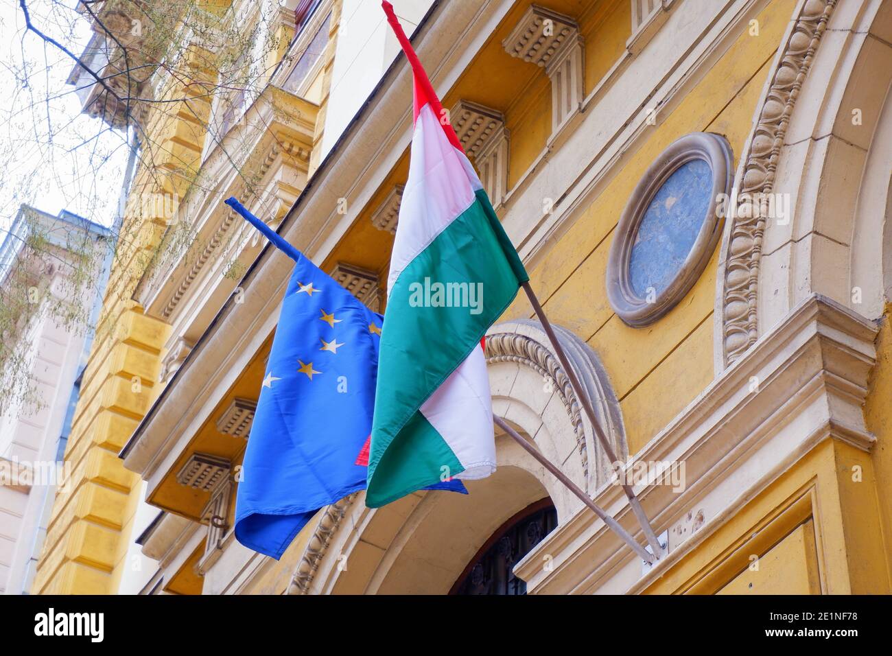 EU and Hungarian national flags on the facade of a yellow building in Budapest, Hungary Stock ...