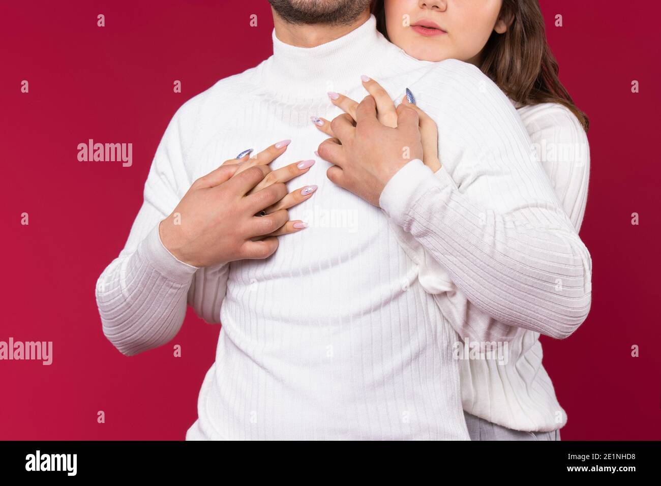 Red background. Enlarged photo of an embrace where girl's hands hug her ...