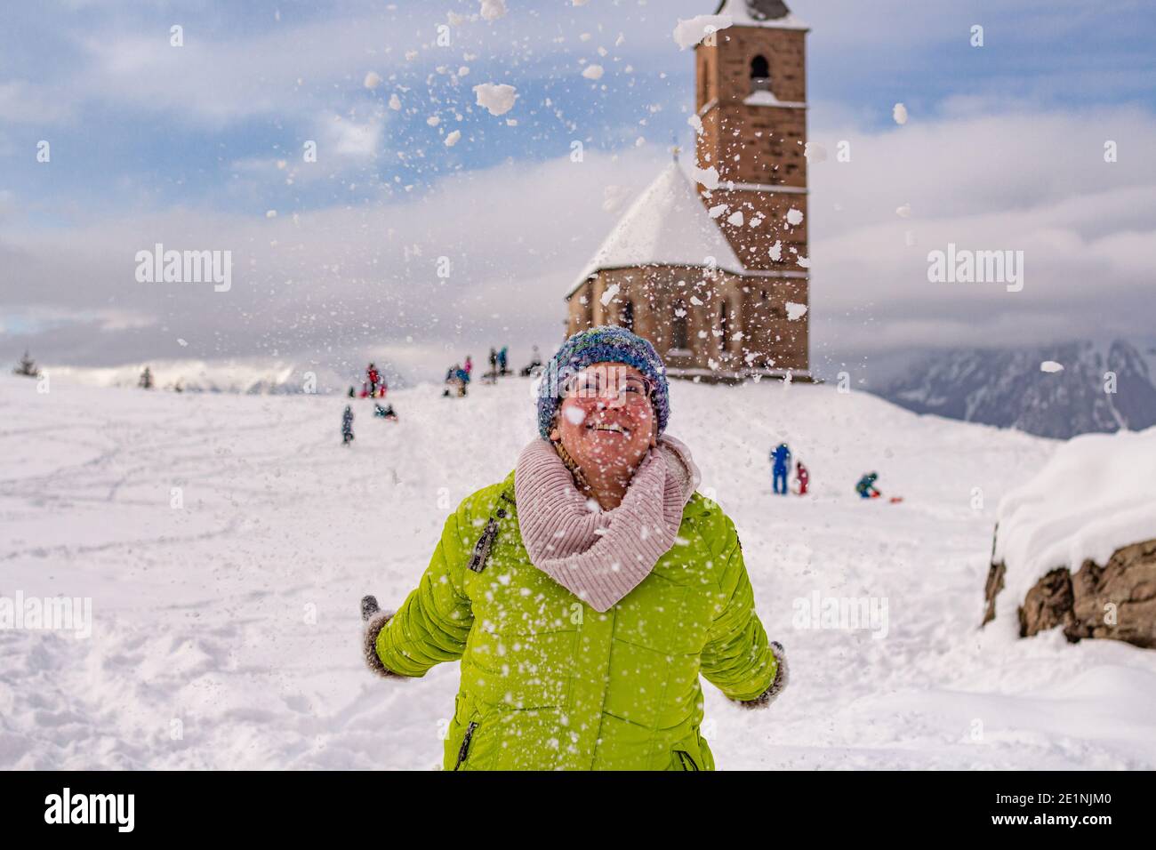 woman having fun in the snow smiling as snow is thrown towards her ...