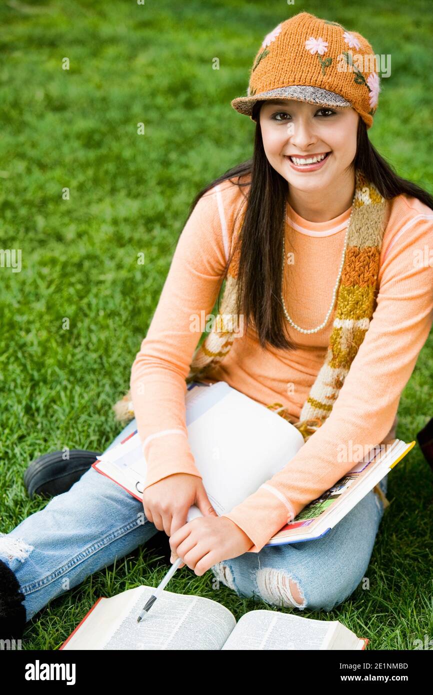Photo of young attractive student studying outside the campus garden ...