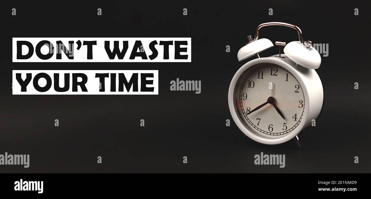 Don't waste time concept text with vintage alarm clock on black ...