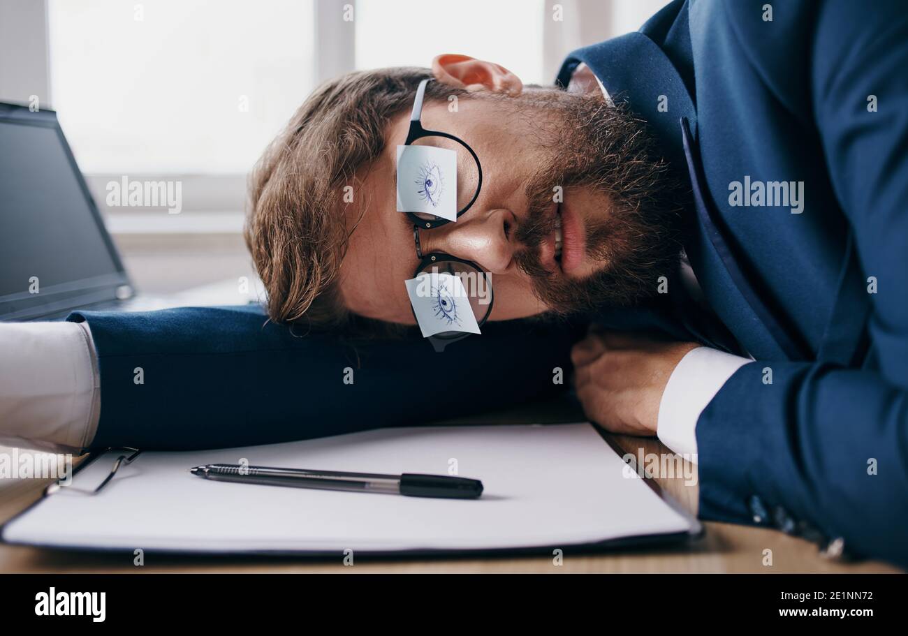 Business man in a suit fell asleep at work at the table in the office ...