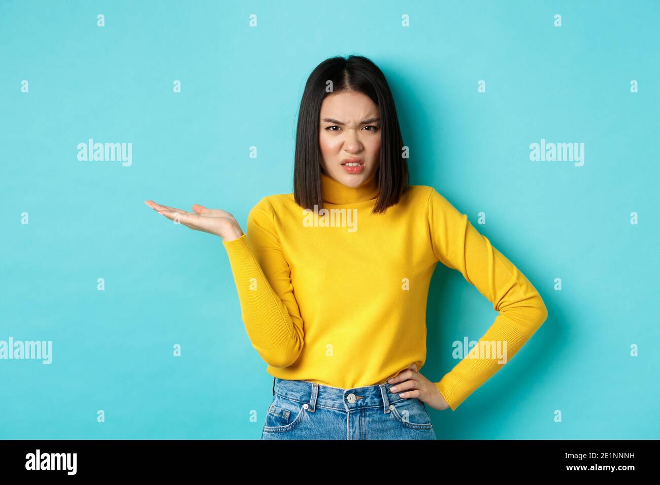 Frustrated and pissed-off asian girl raising hand up and grimacing ...