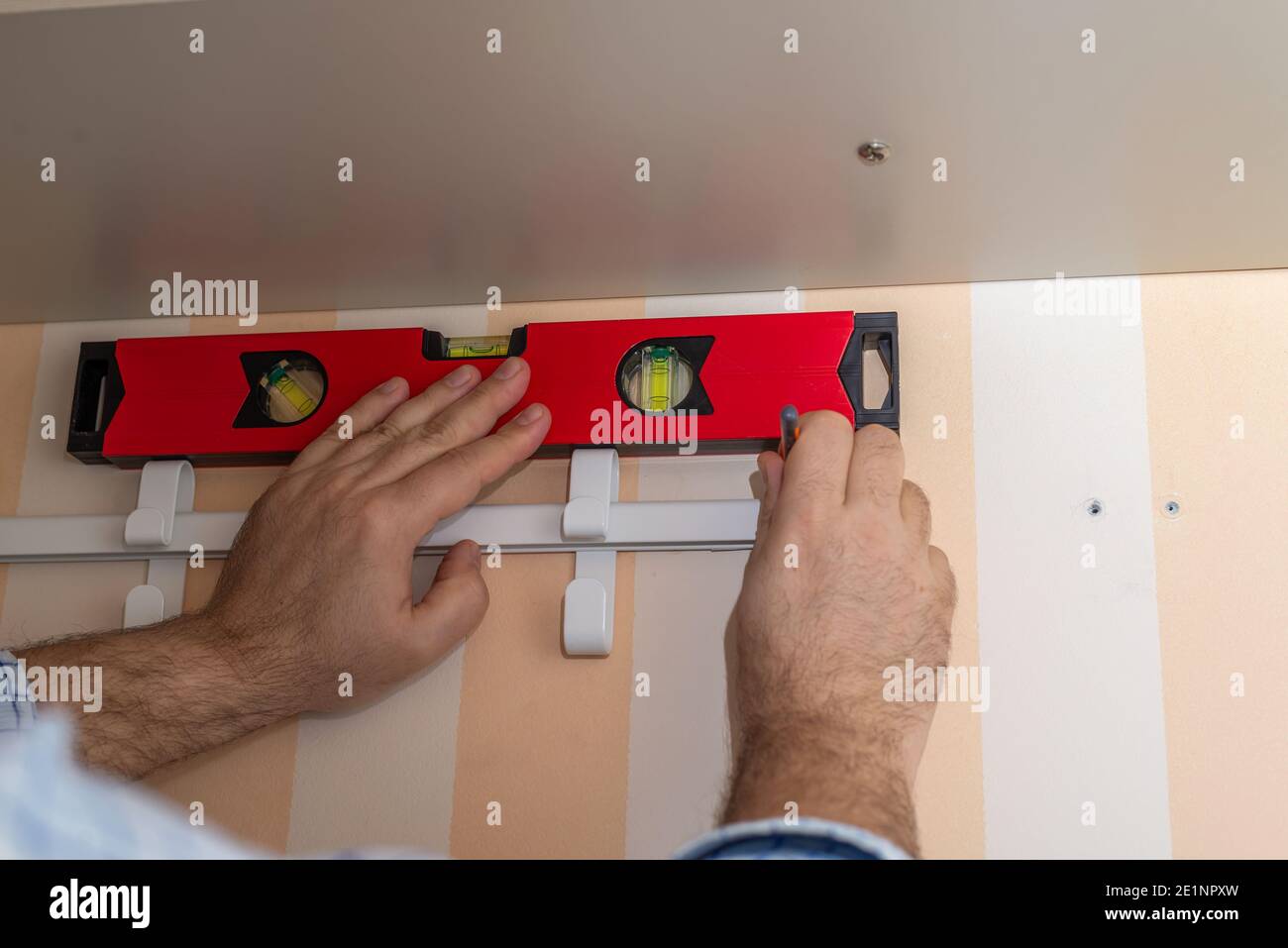 Man marking a position of wardrobe hooks with a bubble level tool Stock ...