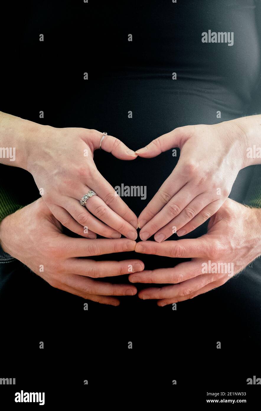 Pregnant women with partner forming hand shaped heart on the bump Stock ...
