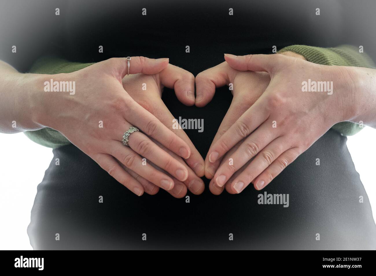 Pregnant women with partner forming hand shaped heart on the bump Stock ...