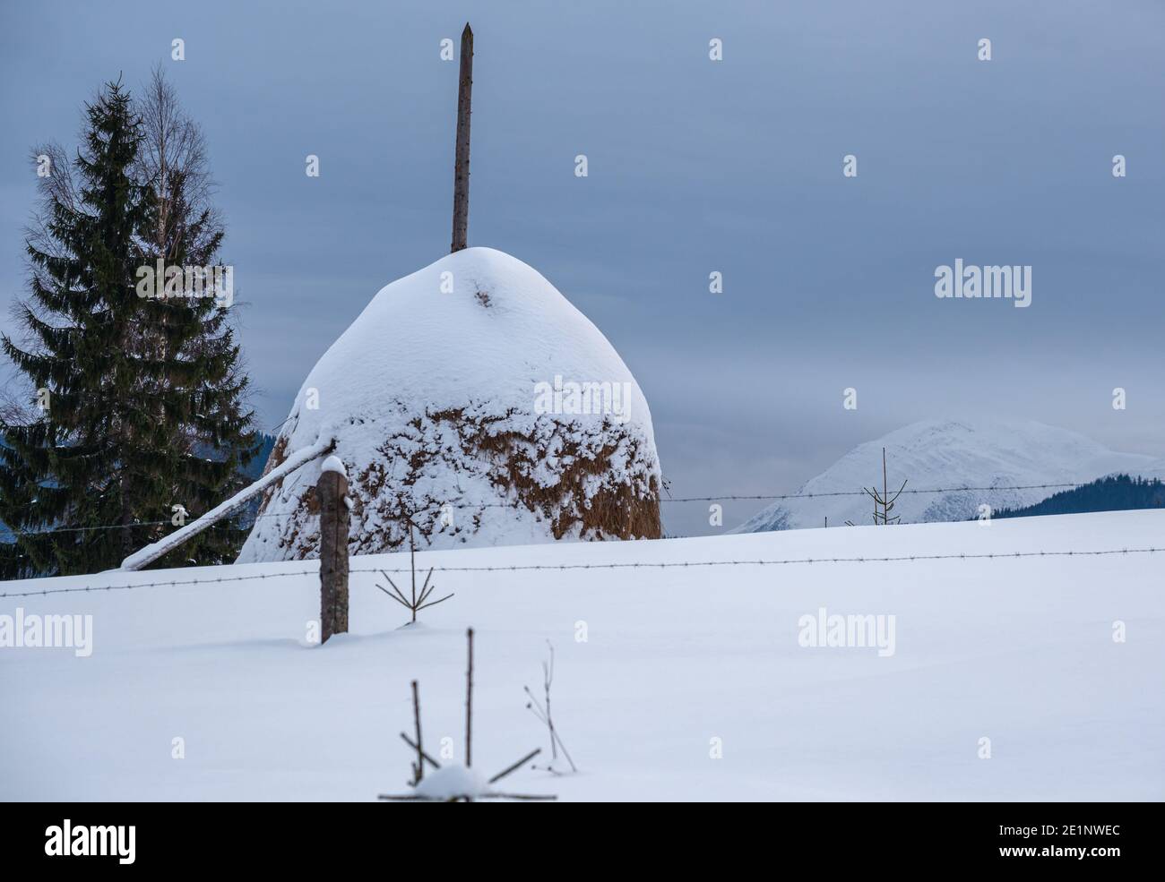 Snow covered haystack on small and quiet mountain village outskirts ...