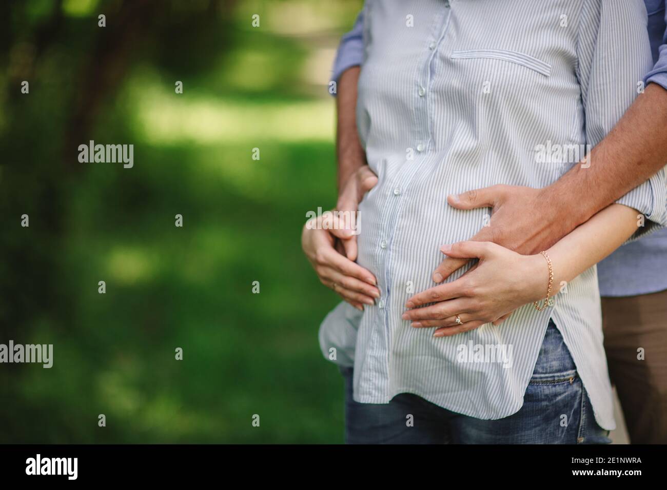 Young couple expecting baby hugging stomach Stock Photo - Alamy