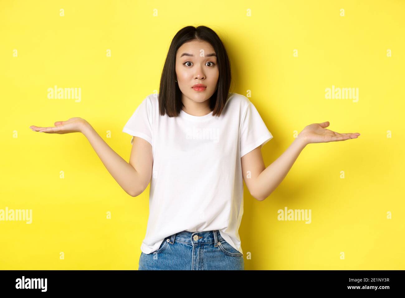 Clueless asian girl shrugging shoulders, spread out hands and looking ...