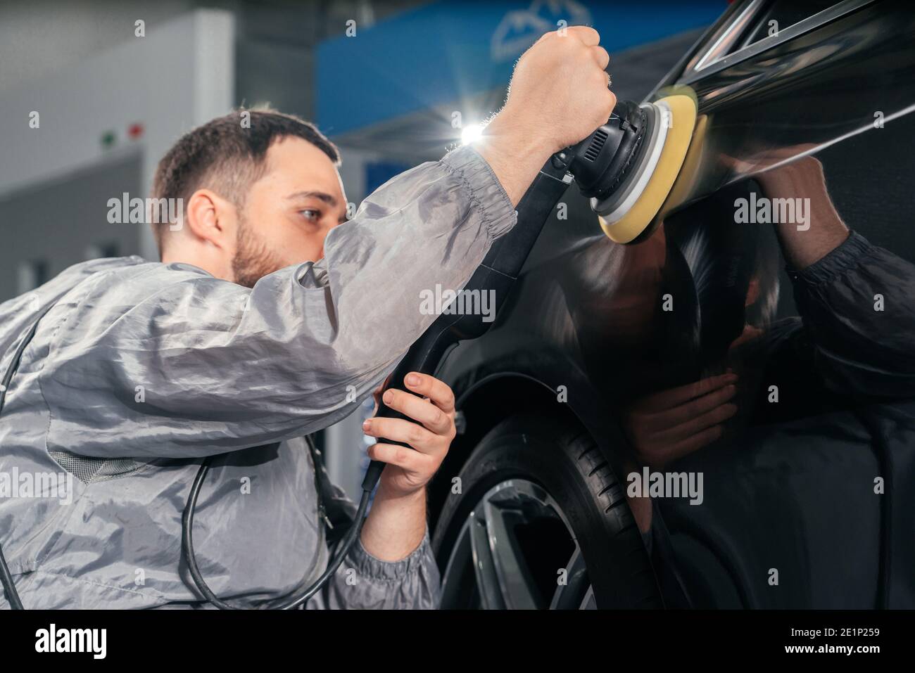 Worker polishing car with special grinder and wax from scratches at the ...