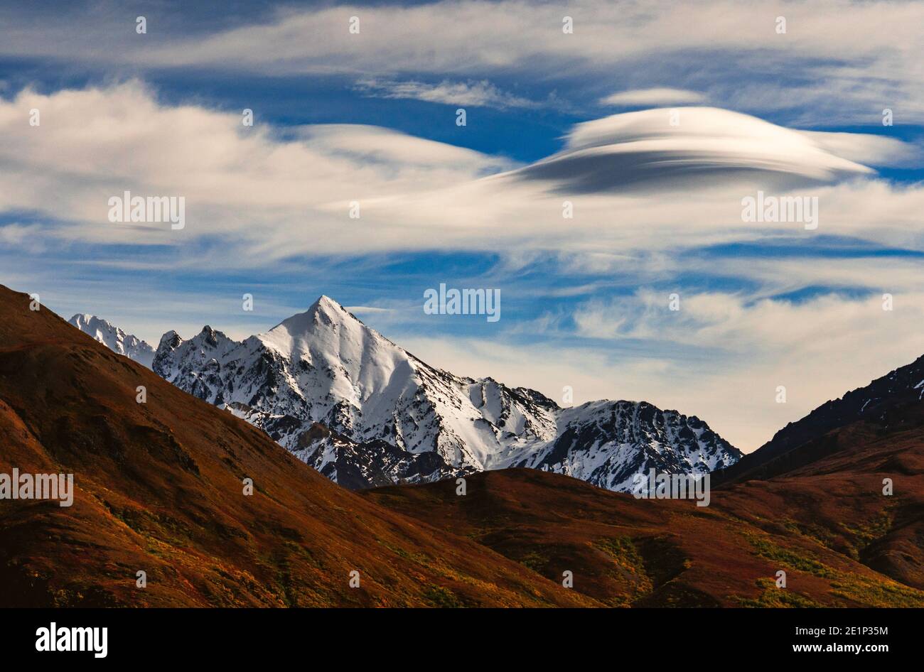 Lenticular clouds form above jagged mountains in a fall landscape Stock ...