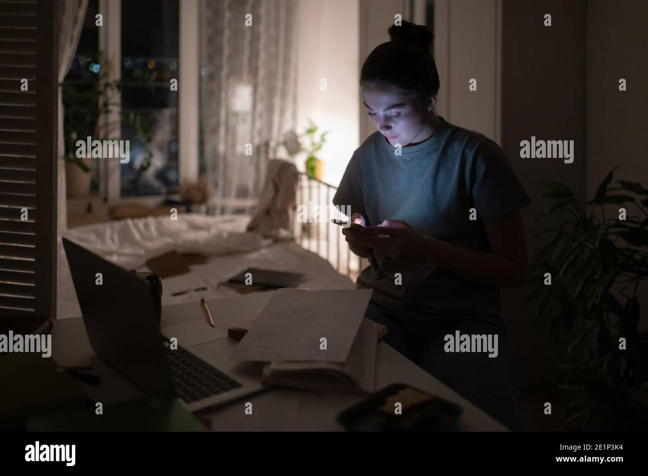 student checking email on mobile phone in dark room during distance ...