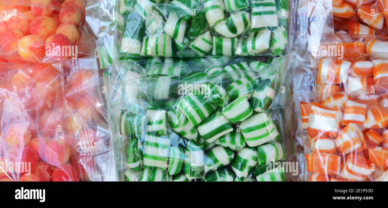 Multicolored candies in an transparent plastic wrap as a background ...