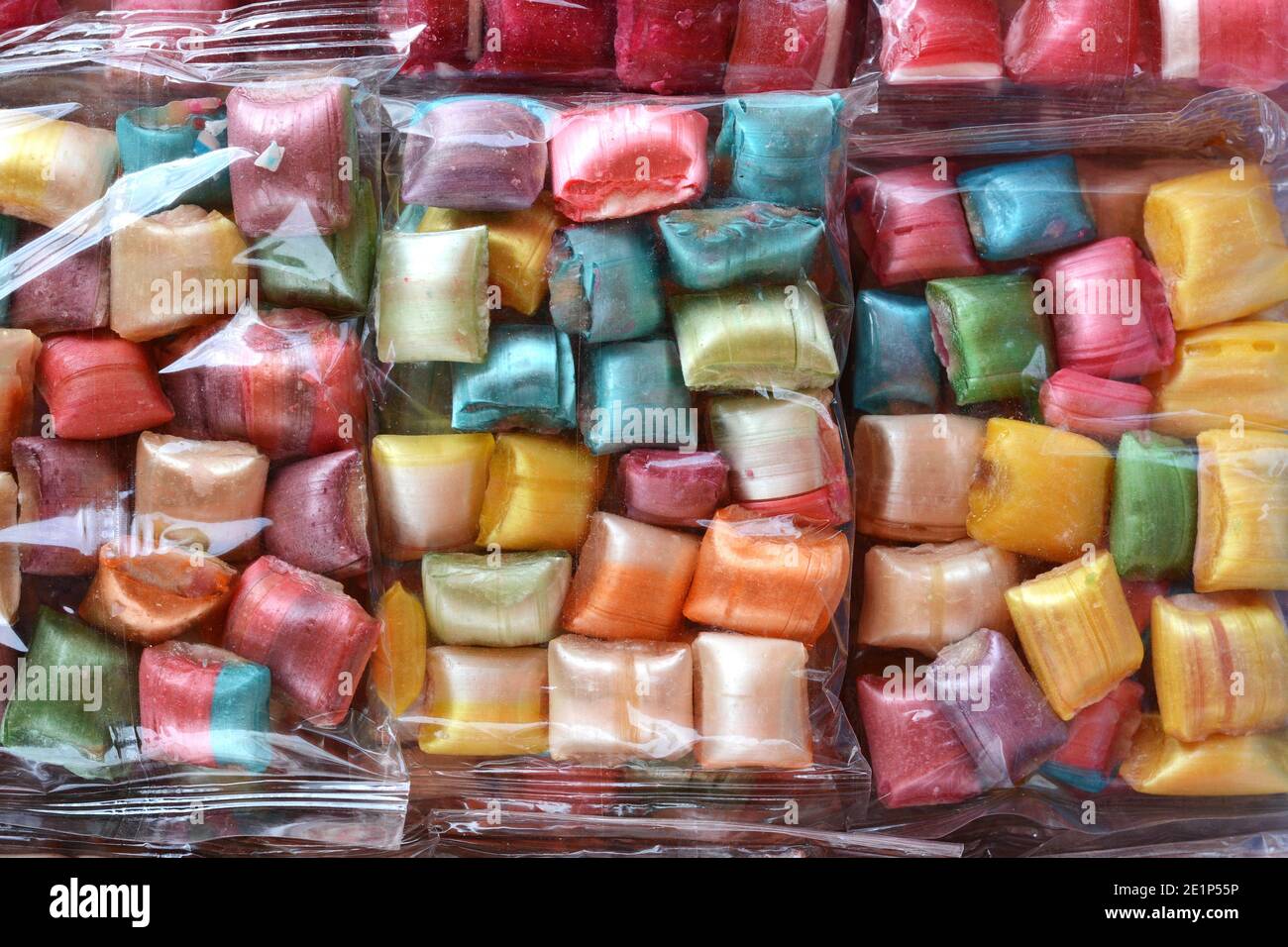 Multicolored candies in an transparent plastic wrap as a background ...