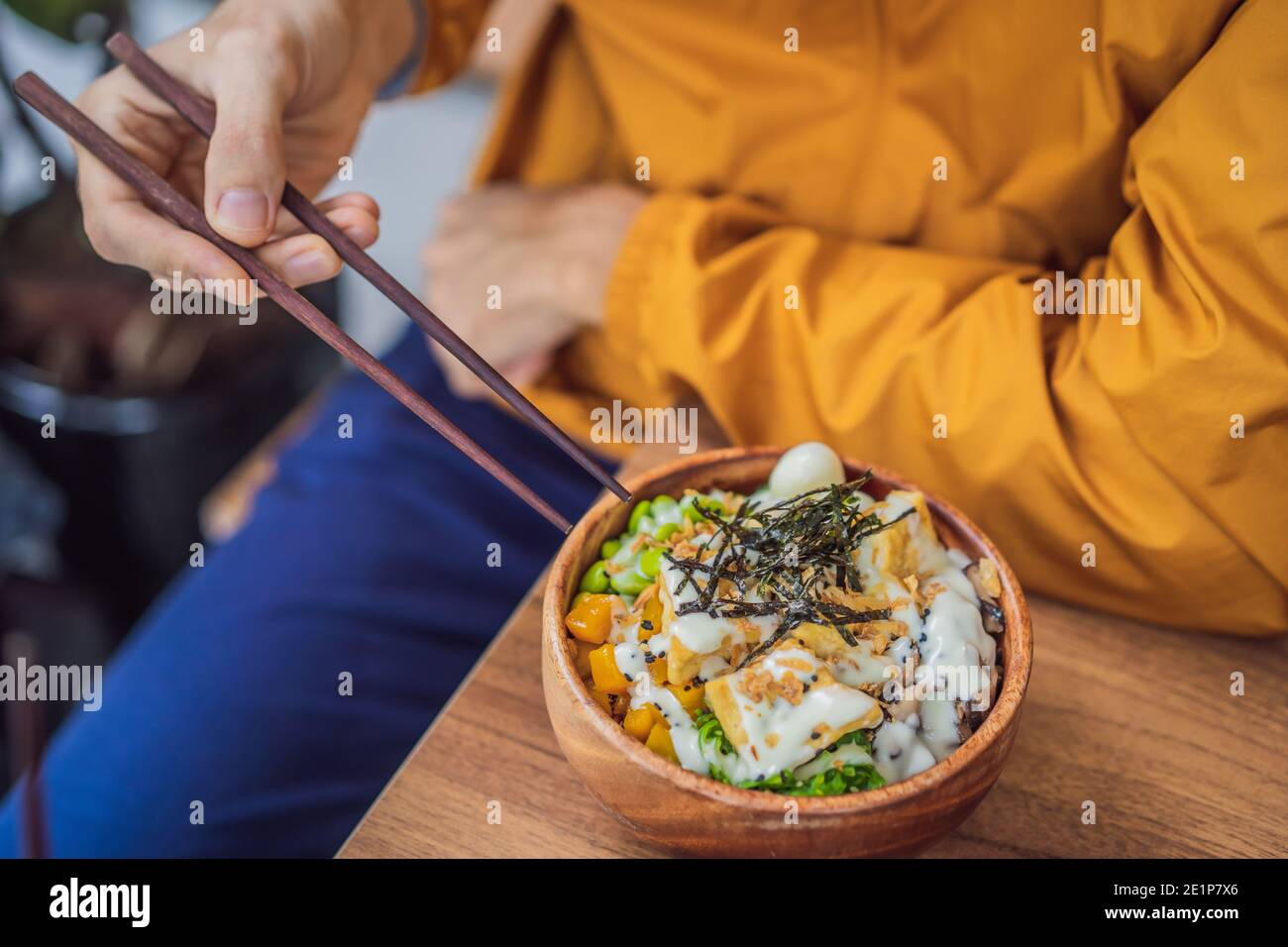 Man eating Raw Organic Poke Bowl with Rice and Veggies close-up on the ...