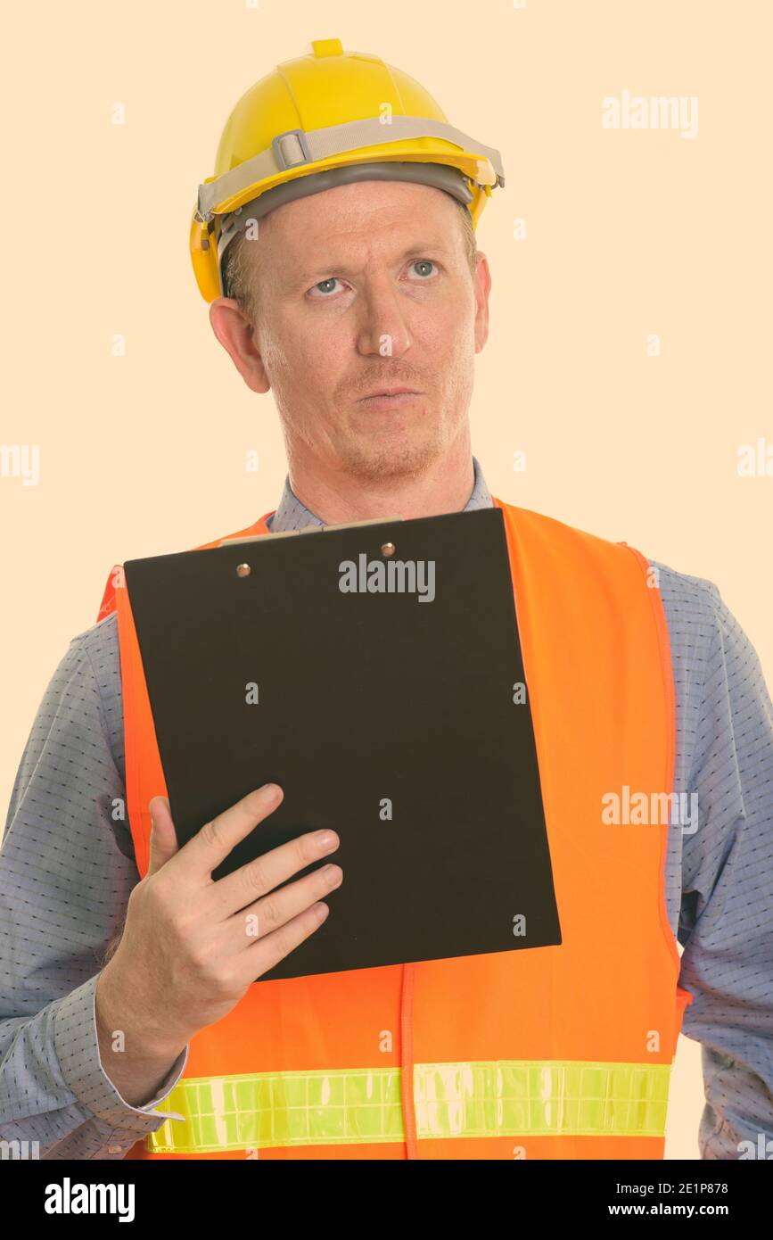 Studio shot of man construction worker holding clipboard while thinking Stock Photo - Alamy