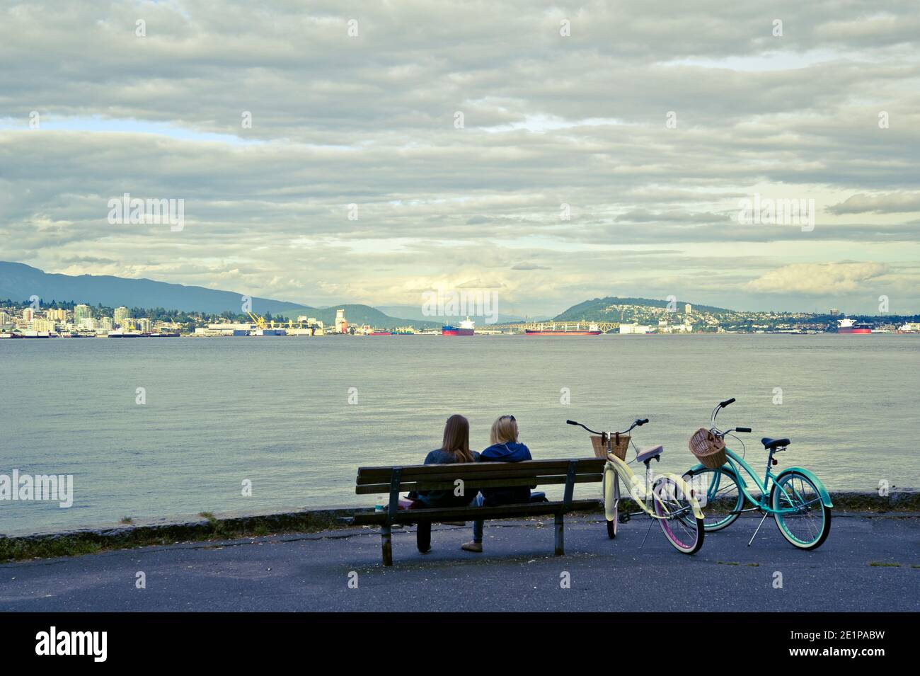 Two female tourists on a bicycle ride resting in Vancouver Stanley Park ...