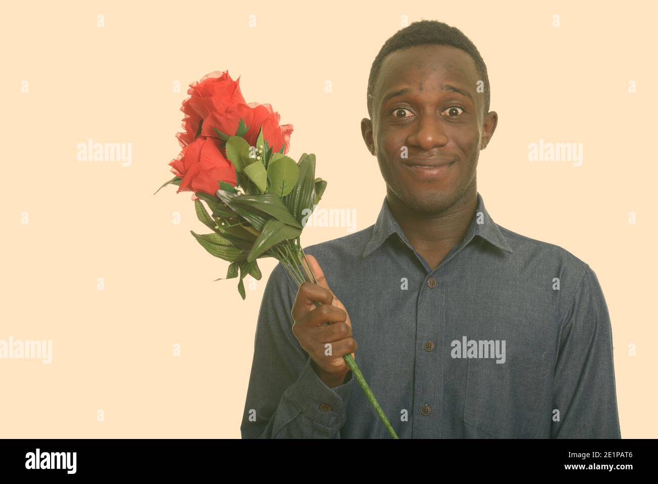 Young happy African man smiling and looking excited while holding red ...