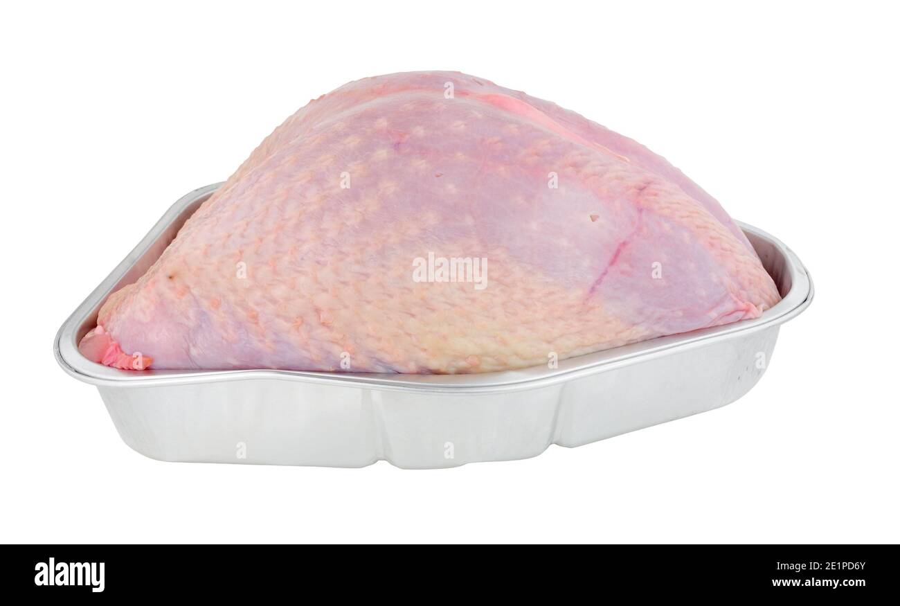 Whole raw turkey crown meat in a foil roasting tray isolated on a white ...
